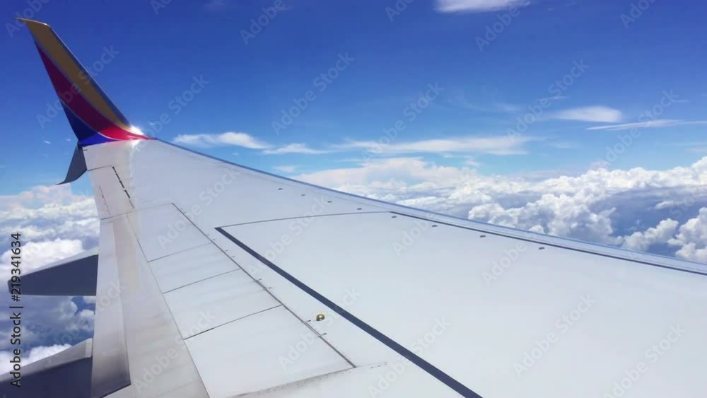 View from plane window of the left wing of plane with clouds in the ...