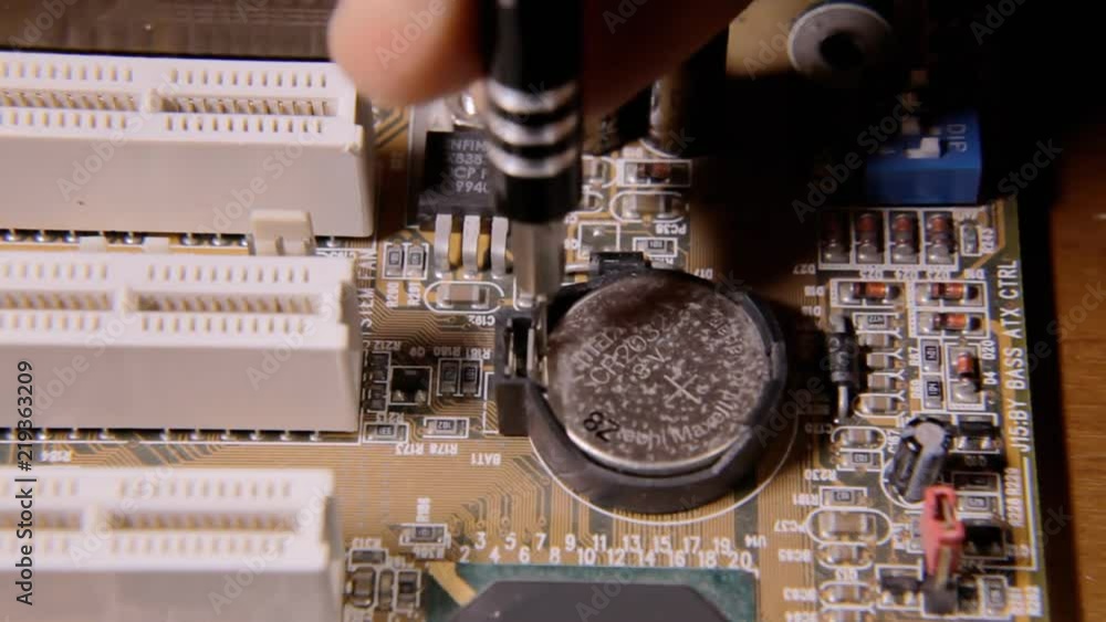 Removing and inserting a CMOS round battery from a computer motherboard ...