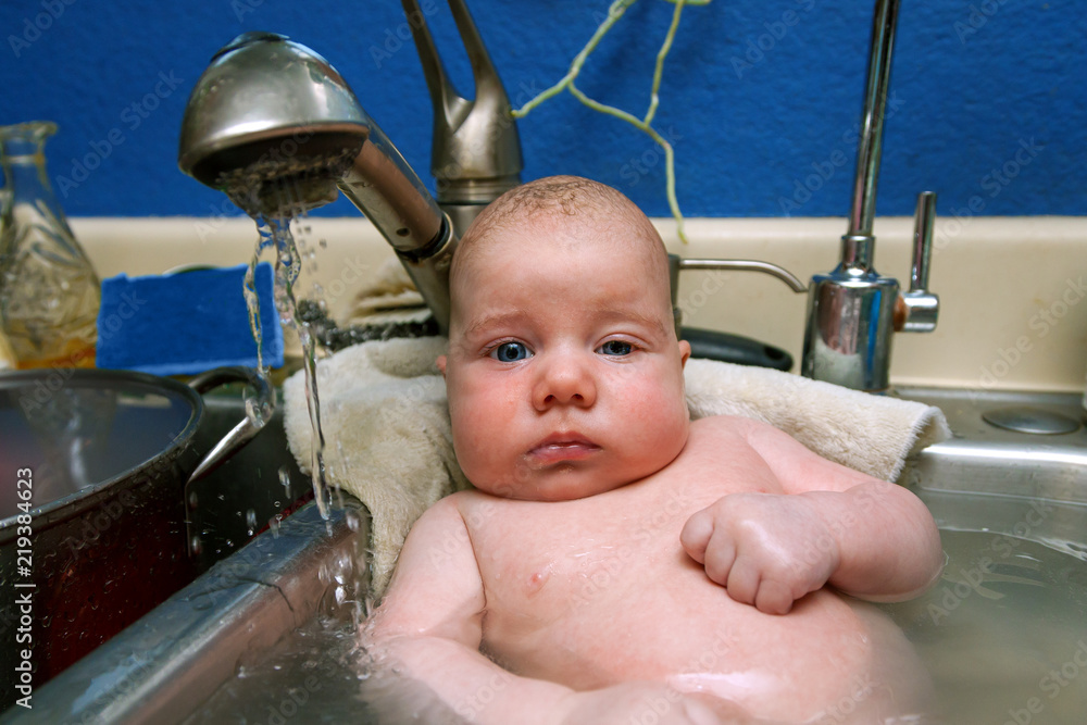 Small Baby Taking a Bath in the Kitchen Sink With Water Dripping Down ...