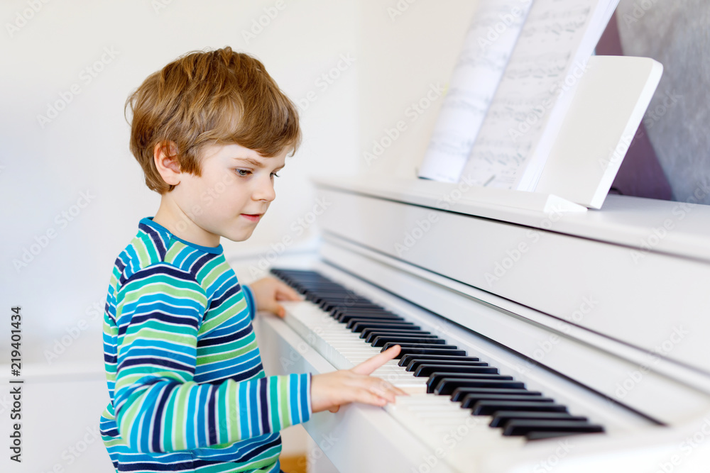 Cute healthy little kid boy playing piano in living room or music ...