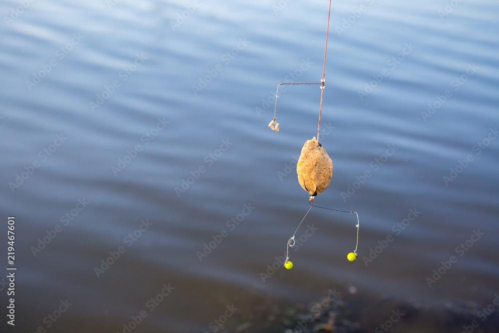 Feeding trough for fish against background of lake. Feeder fishing on ...