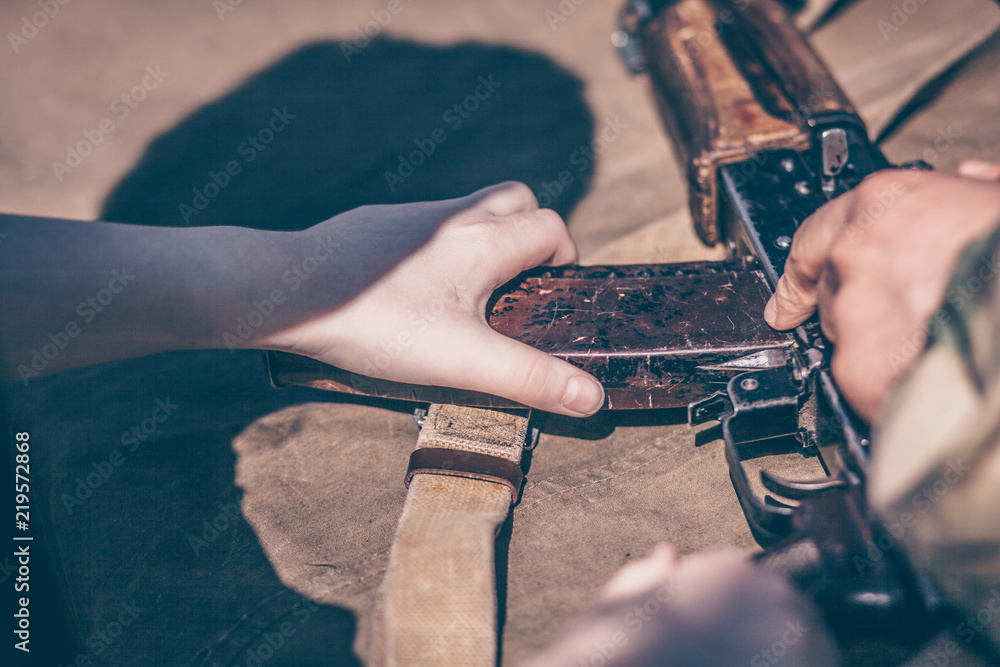 The boy performs disassembly, cleaning and assembly of AK-47, an ...