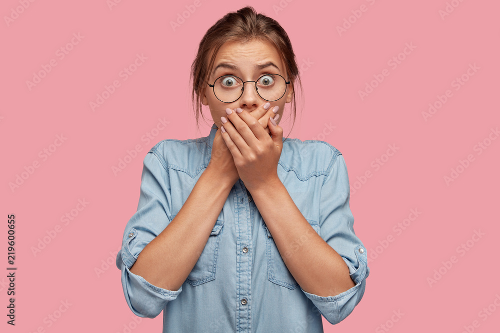 Stunned crazy housewife stares with scared expression, covers mouth ...