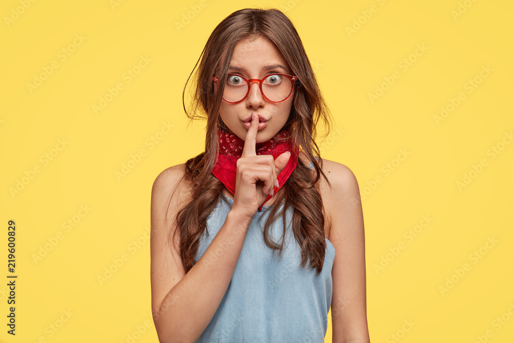 Shh! Cute surprised young woman asks for silence, makes hush gesture ...