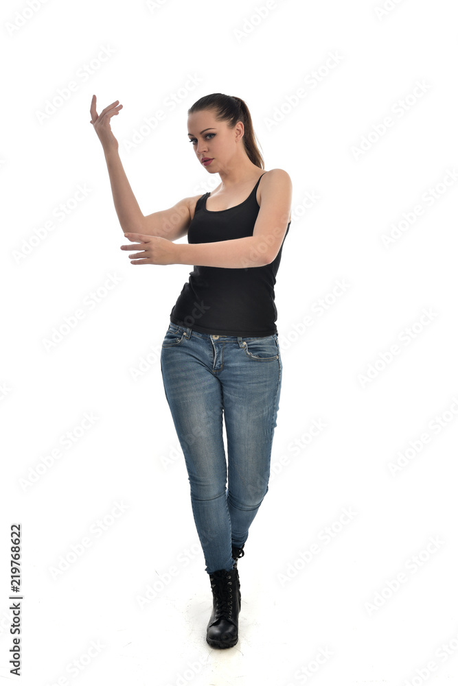 full length portrait of brunette girl wearing black single and jeans ...