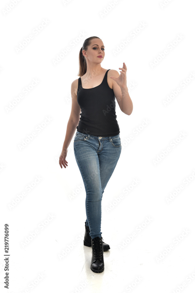 full length portrait of brunette girl wearing black single and jeans ...