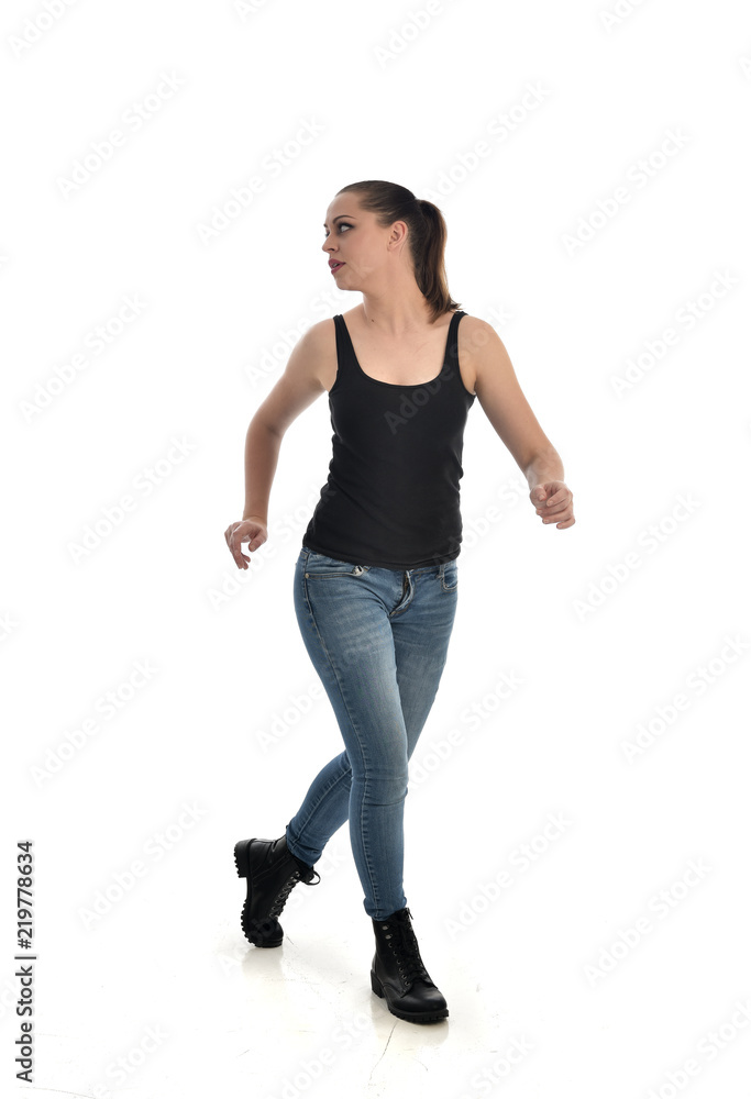 full length portrait of brunette girl wearing black single and jeans ...
