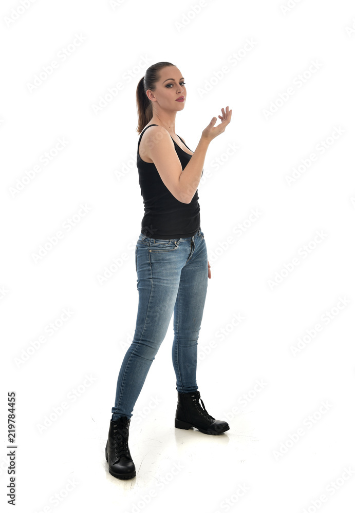 full length portrait of brunette girl wearing black single and jeans ...