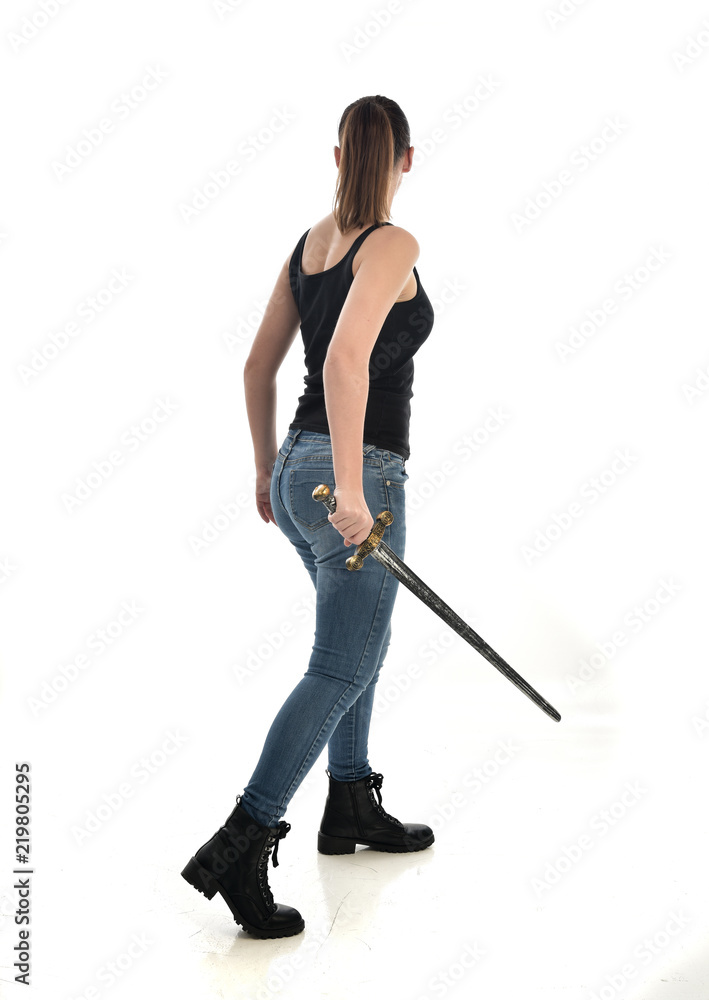 full length portrait of brunette girl wearing black single and jeans ...