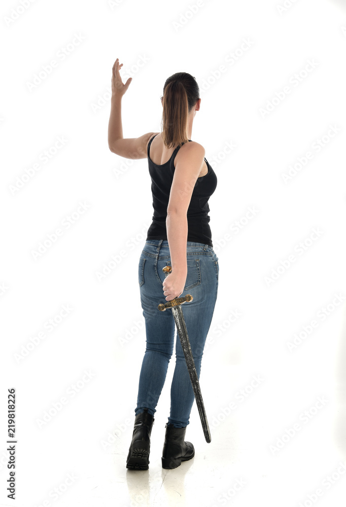 full length portrait of brunette girl wearing black single and jeans ...