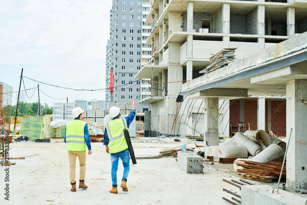 Back view full length portrait of two construction workers wearing ...