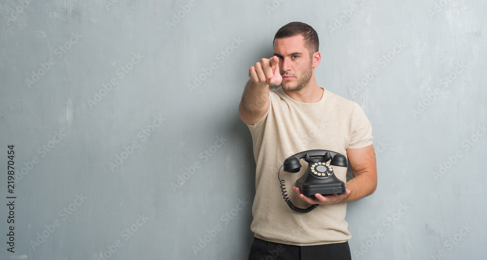 Young caucasian man over grey grunge wall calling using vintage ...