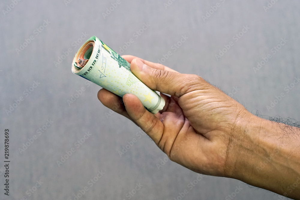 Hand of office worker gives a bribe roll euro banknote to an employee ...