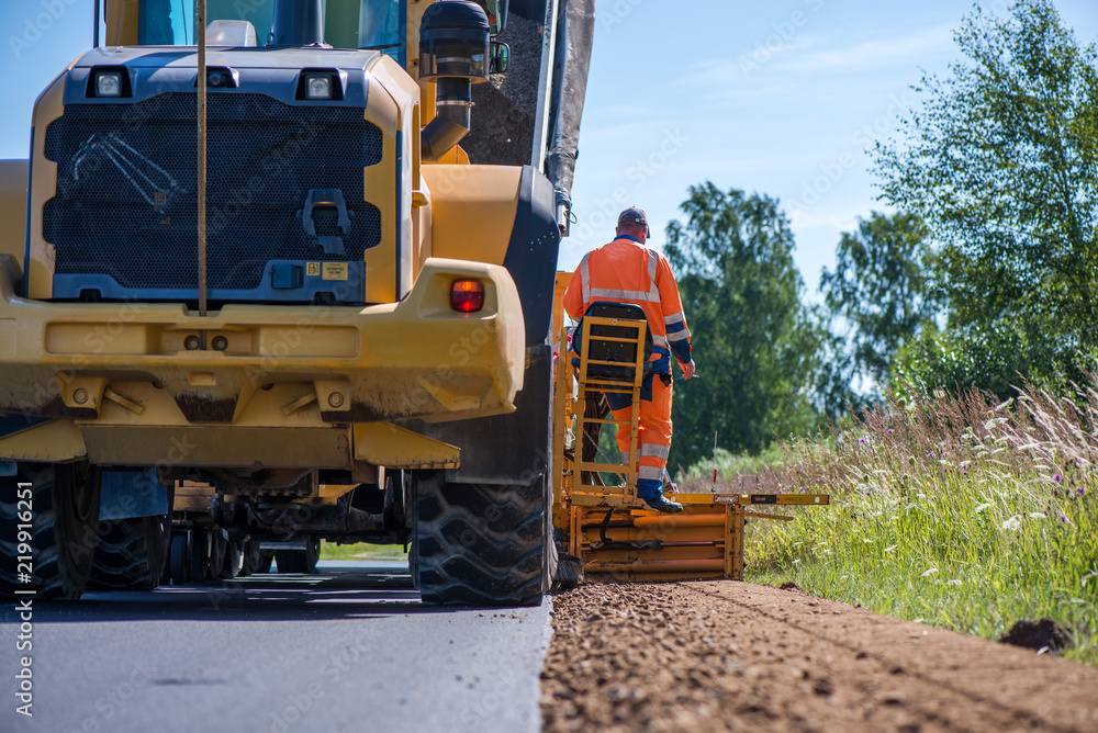 Road construction workers repairing highway road on sunny summer day ...