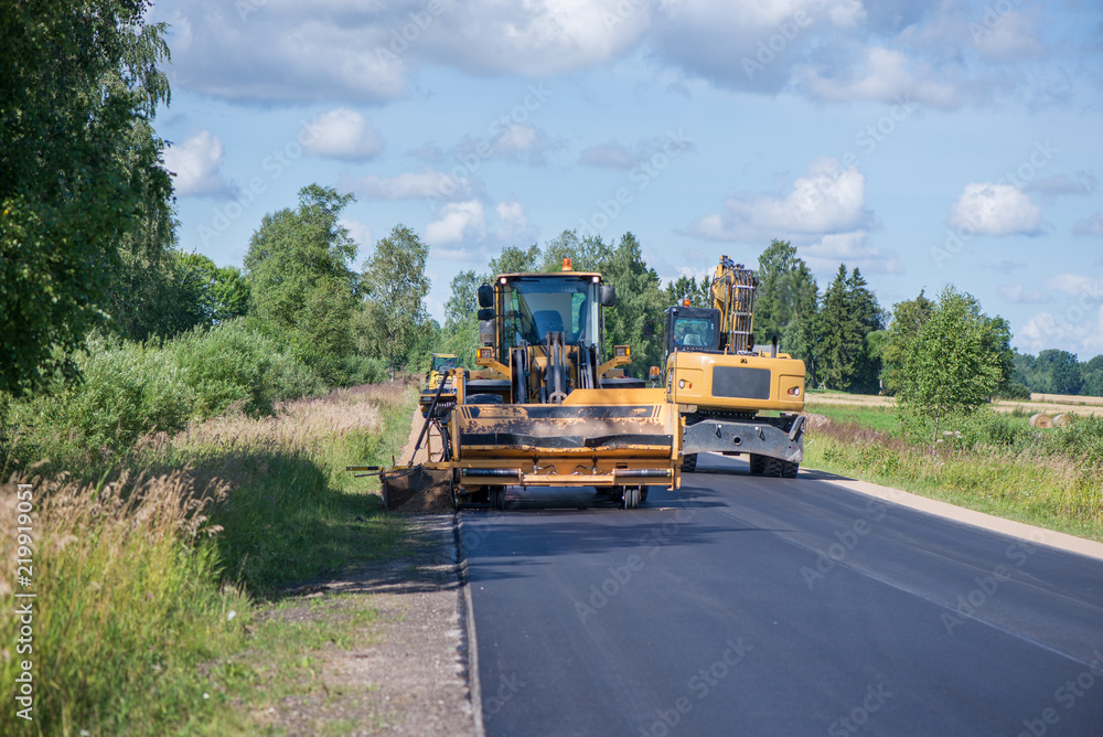 Road construction workers repairing highway road on sunny summer day ...