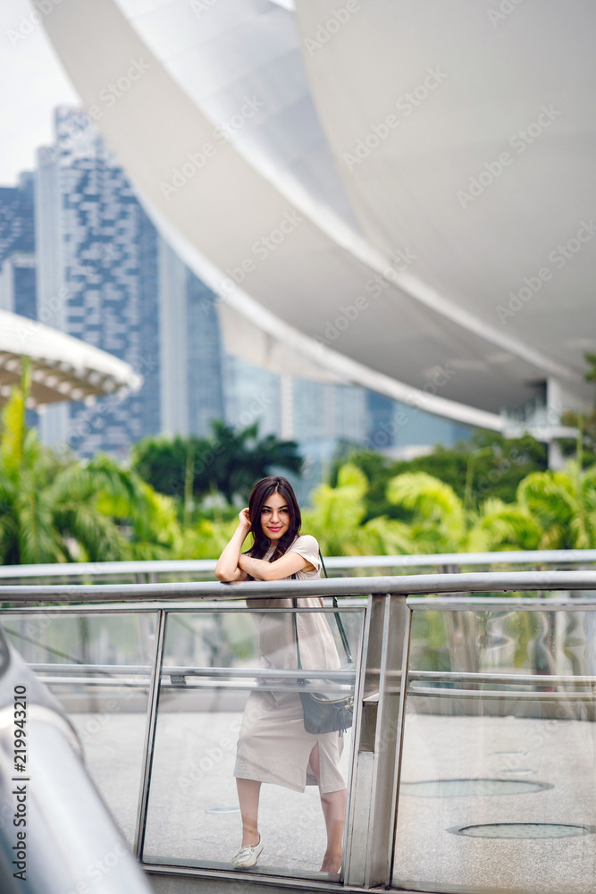 A young Japanese Asian tourist woman leans against a railing on a ho ...