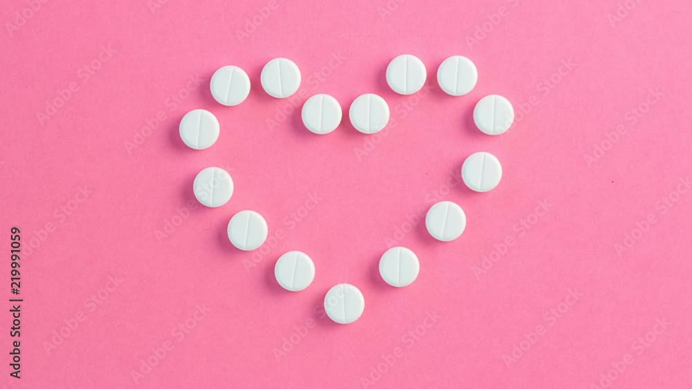 Tablets line up in the shape of a heart on a pink background Stock ビデオ ...
