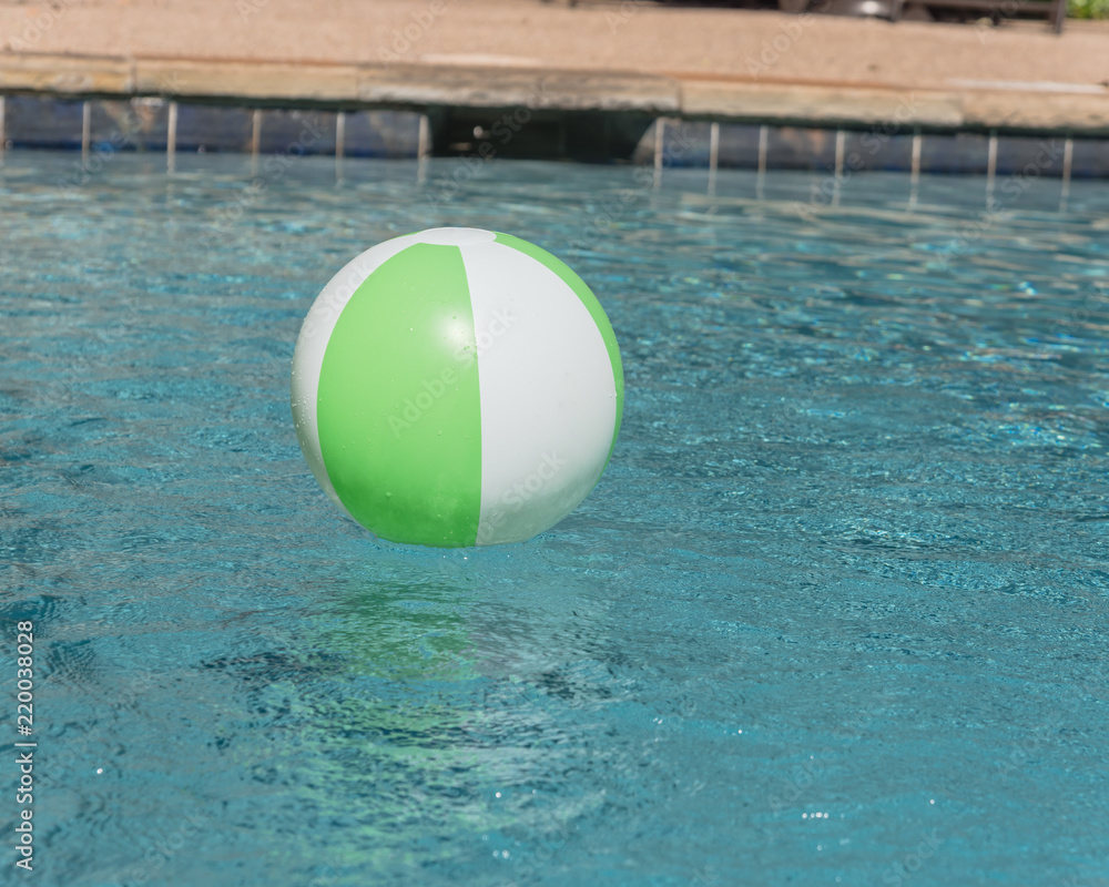 One bright green beach ball near swimming pool coping edge with depth ...
