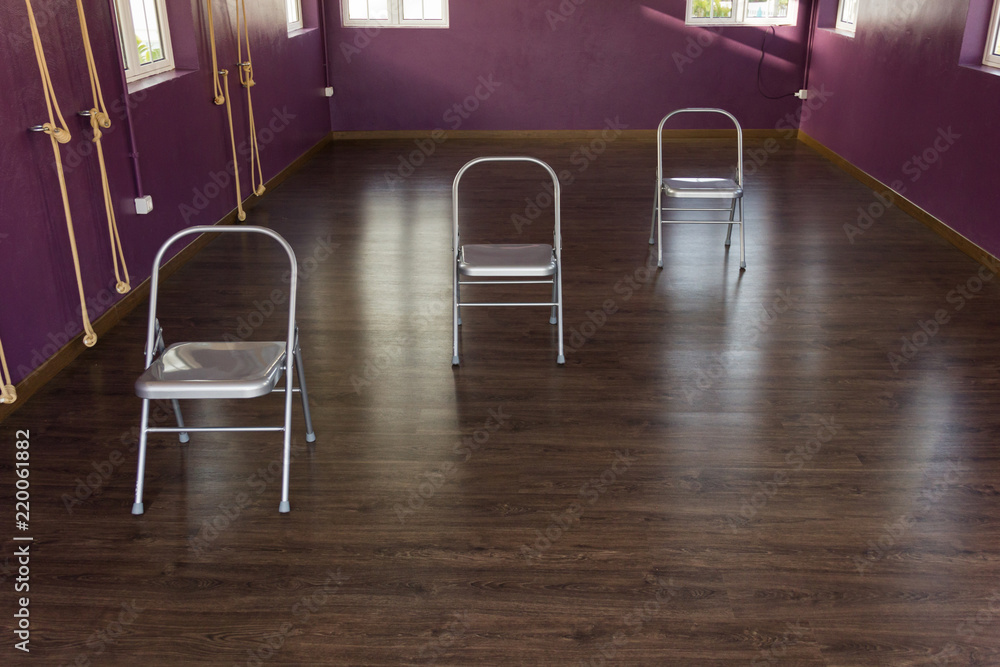 Three chairs in empty yoga studio. Plank wood floor and purple wall ...