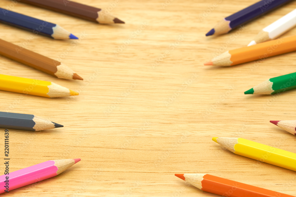 Colorful wooden pencils surround a circle on a wood background. Make a ...