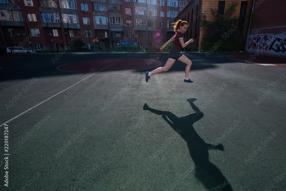 Red-haired young girl runs in the stadium. Student delivers standards ...