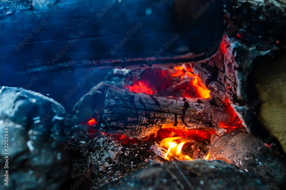 Smoldered logs burned in vivid fire. Atmospheric background with orange ...