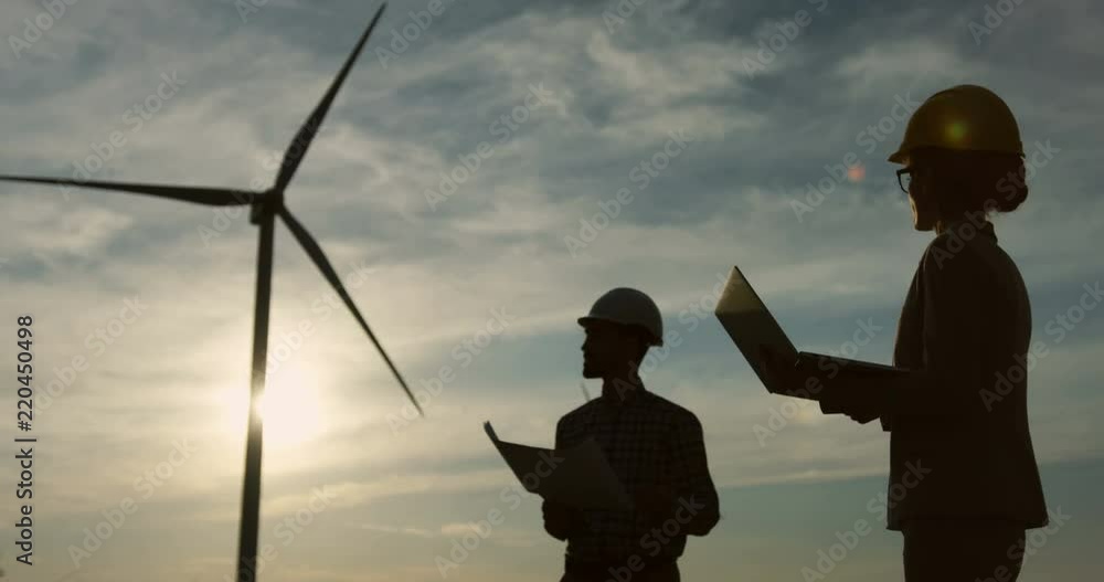 Male engineer in a helmet holding some documents and drawings while ...