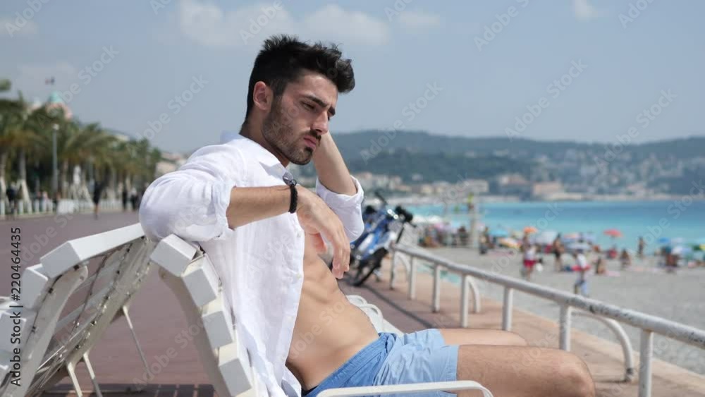 Attractive fit athletic young man soaking in the sun on seaside ...