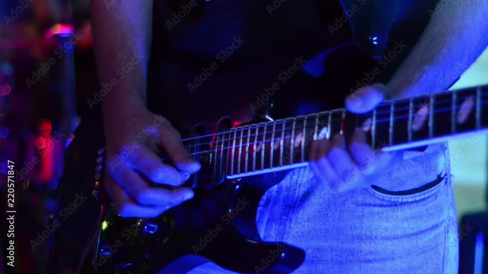 Male singer and guitarist playing guitar at rock concert. Stage lights ...