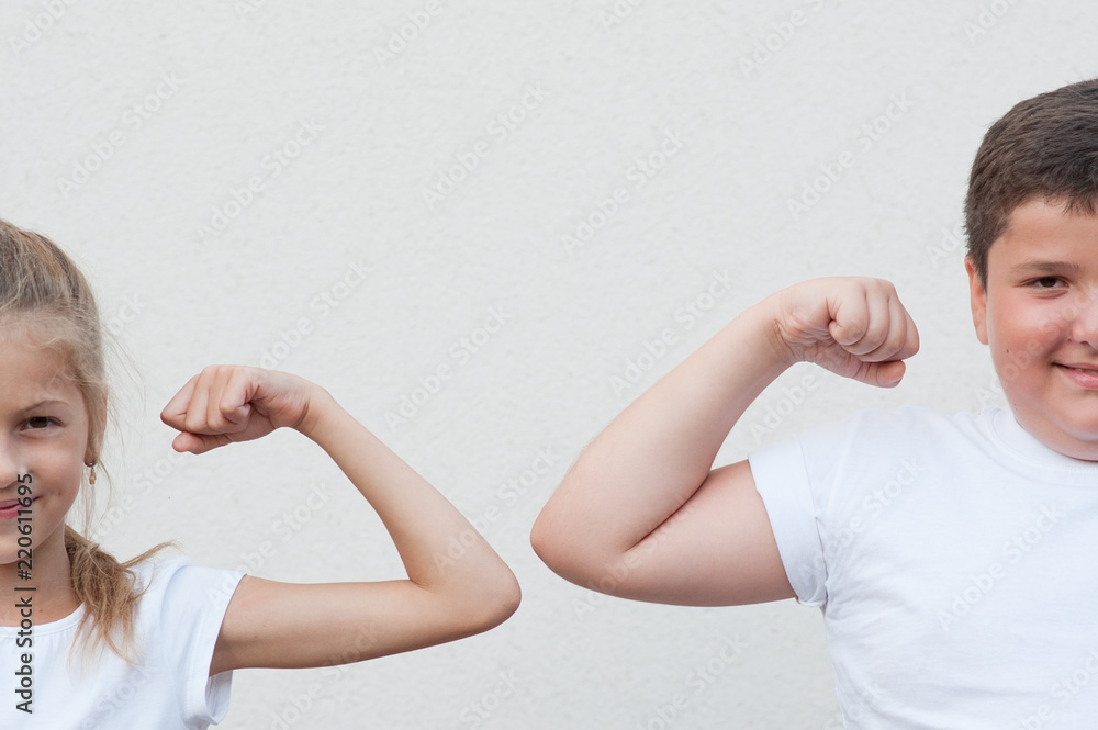 two beautiful kids fat boy and thin girl showing muscles on copy space ...