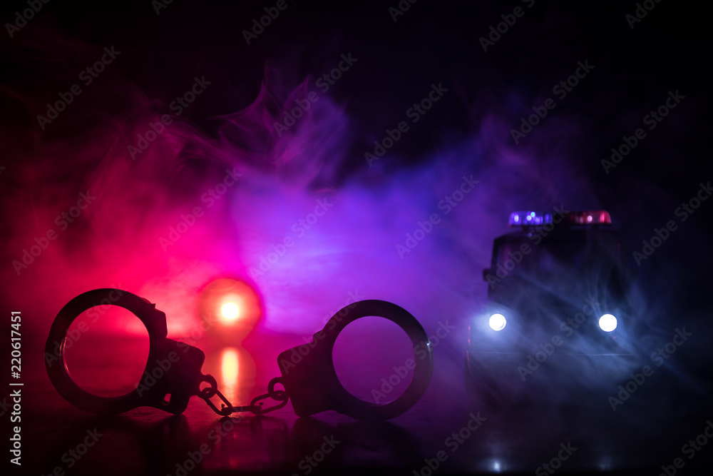 Closed handcuffs on the street pavement at night with police car lights ...