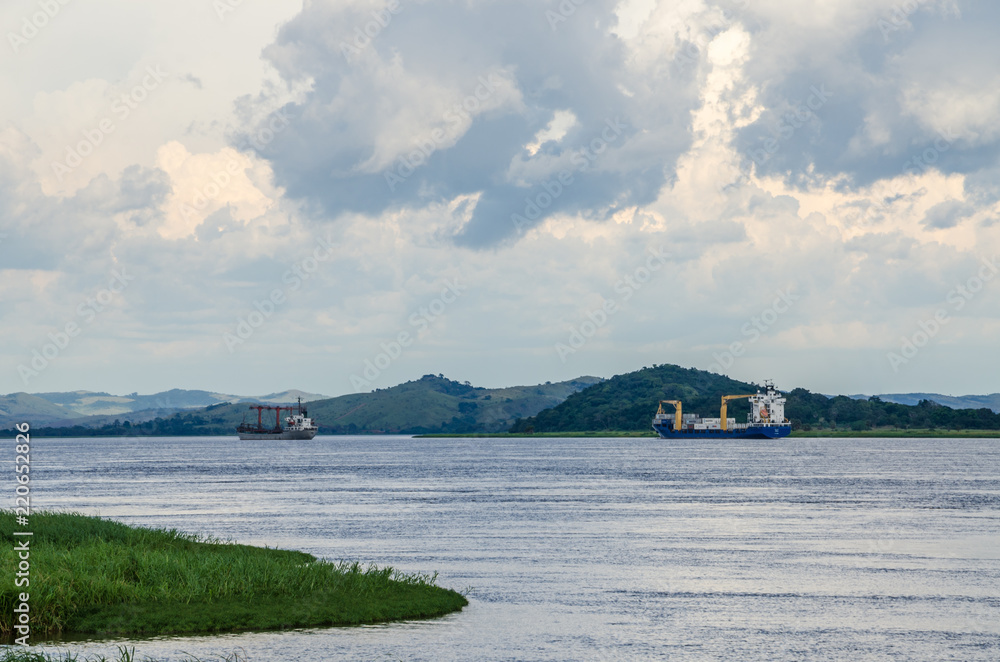 Container cargo ships on mighty Congo river with dramatic cloudy sky ...