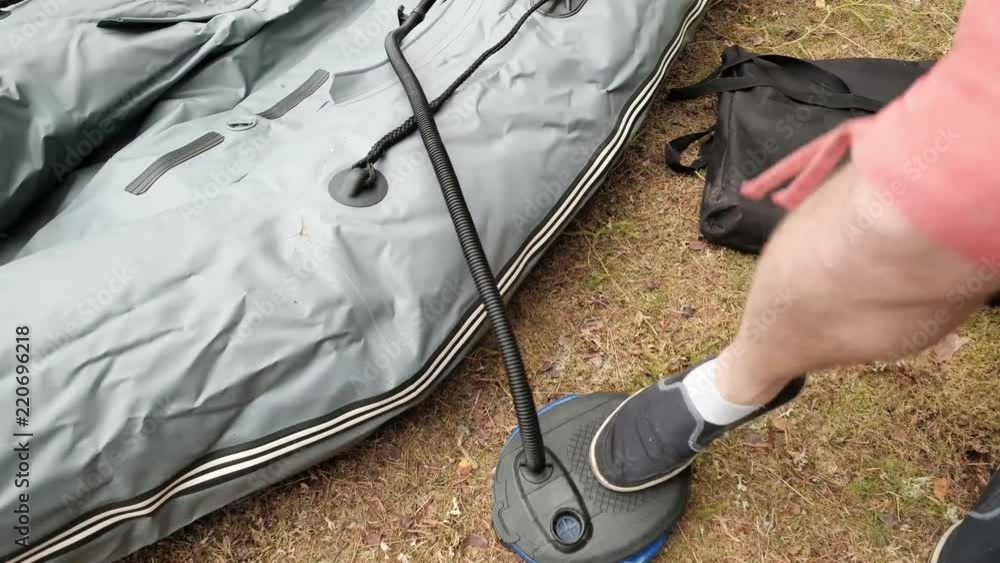 Man inflating rubber boat for fishing by his leg on the shore. Get ...