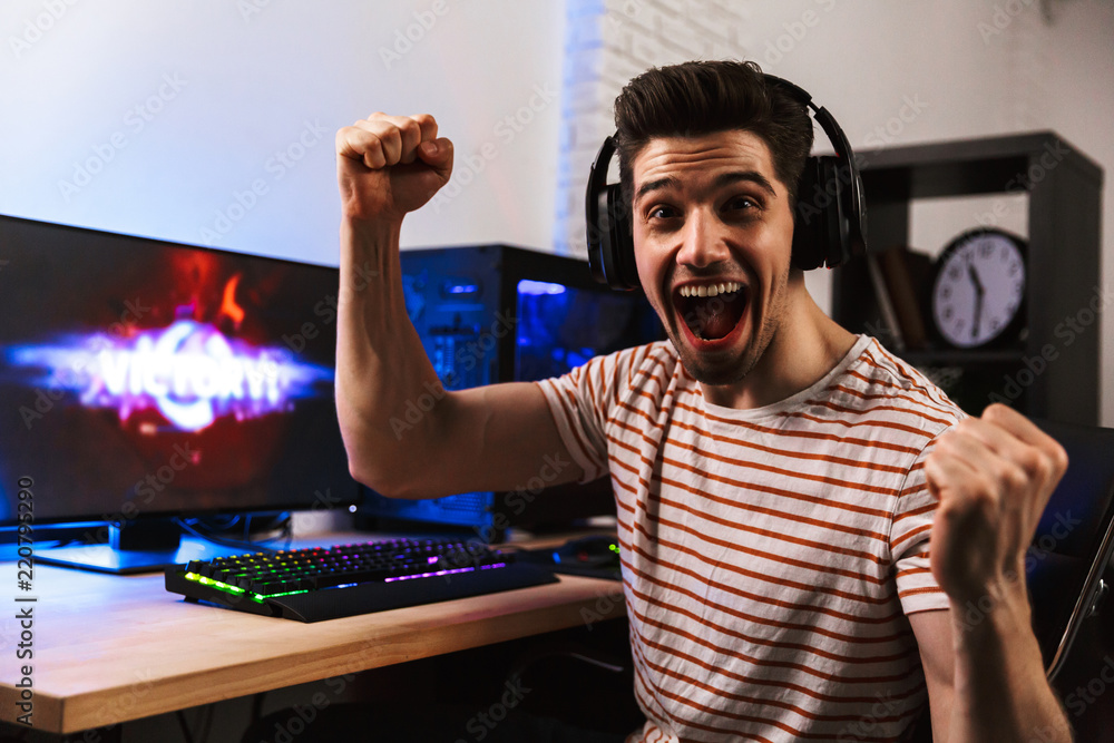 Cheerful gamer playing video games on computer and rejoices Stock Photo ...