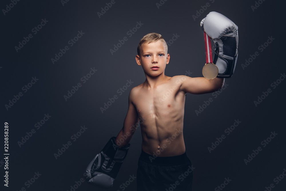 Young shirtless boy boxer in boxing gloves holds a golden medal posing ...