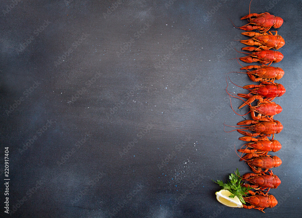 Row of boiled cooked crayfish crawfish ready to eat on black deep blue ...