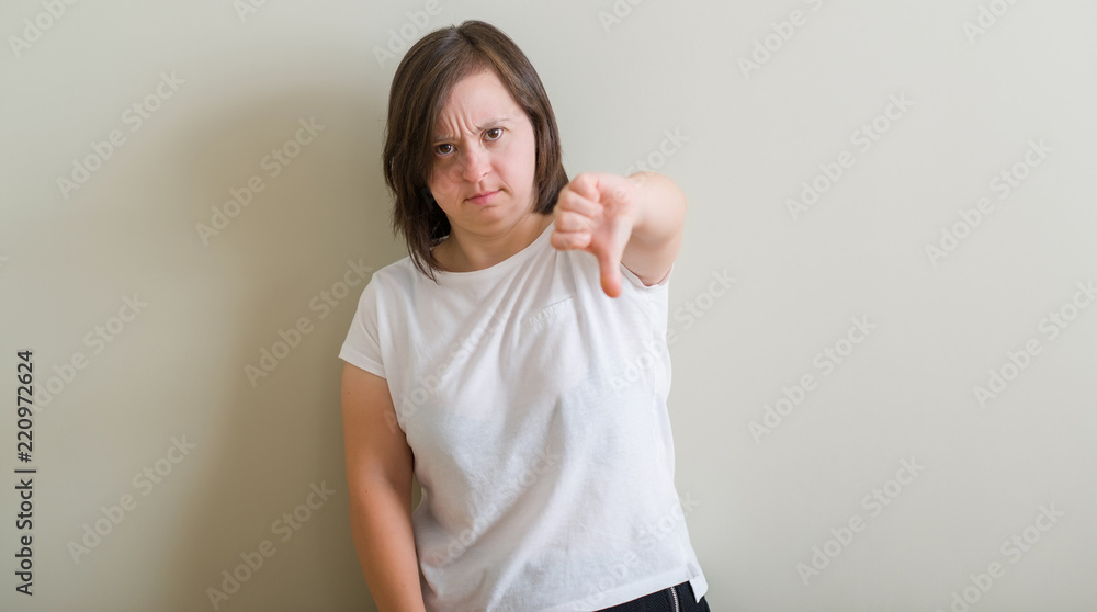 Down syndrome woman standing over wall looking unhappy and angry ...