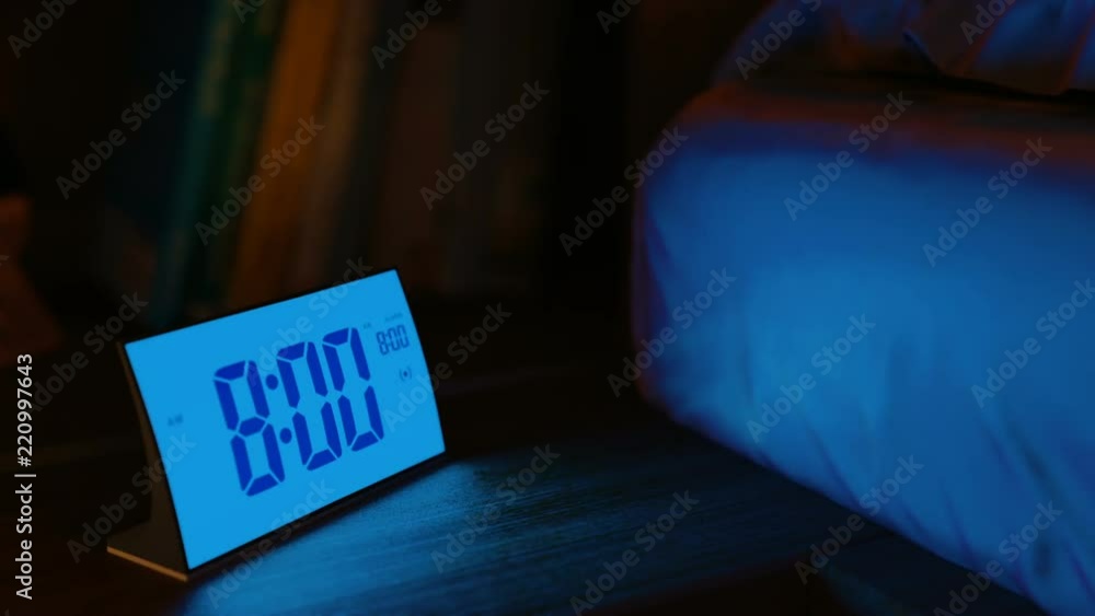 Digital alarm clock in a bedroom waking up at 8 AM. Close-up view. The ...