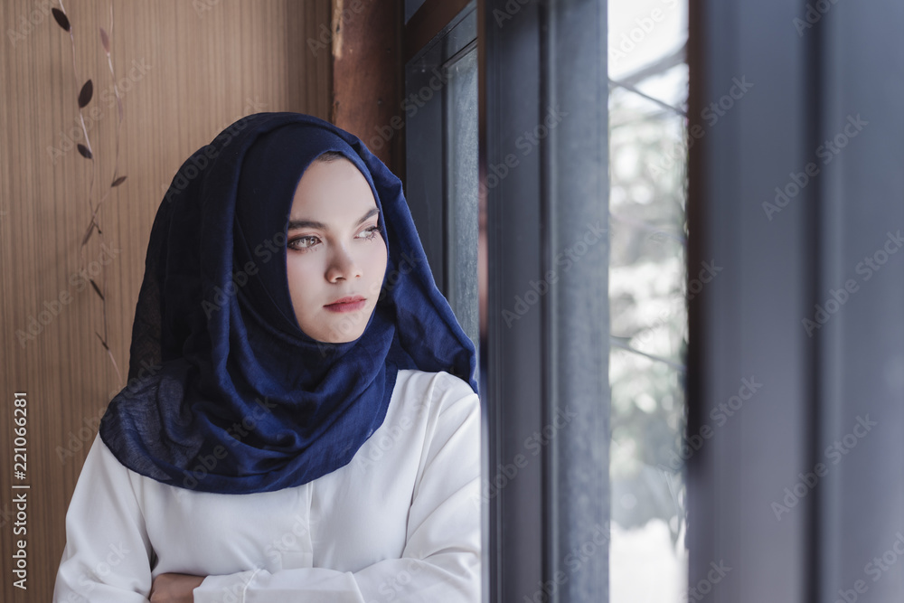 Sad and depressed muslim woman dark blue hijab looking outside window ...