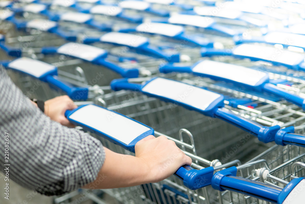 Male hand shopper pulling shopping cart (trolley) from row in ...