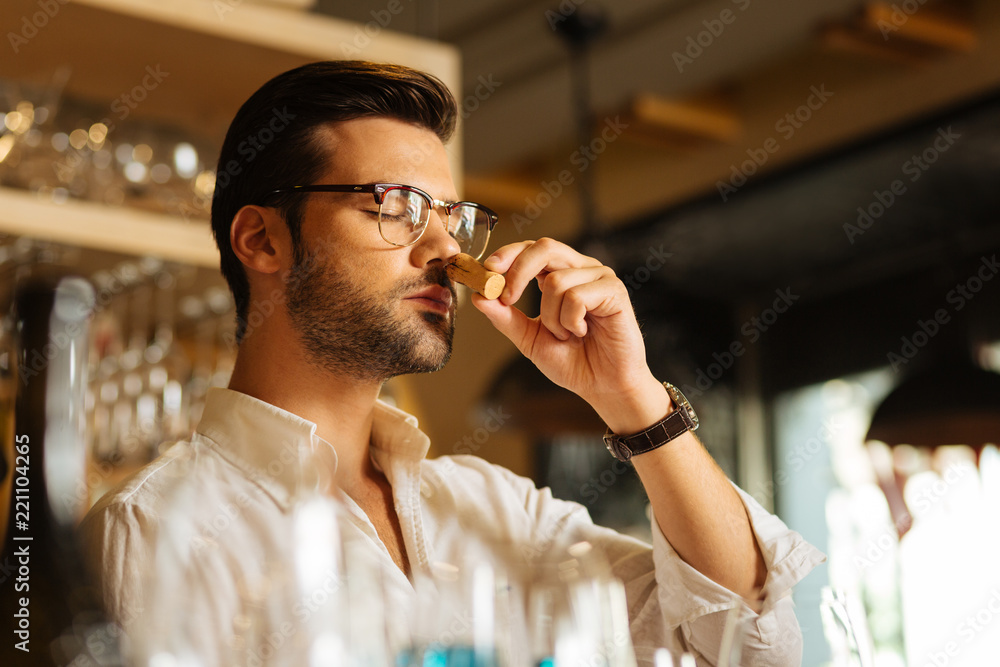 Checking the smell. Pleasant handsome man putting a wine cork to his ...