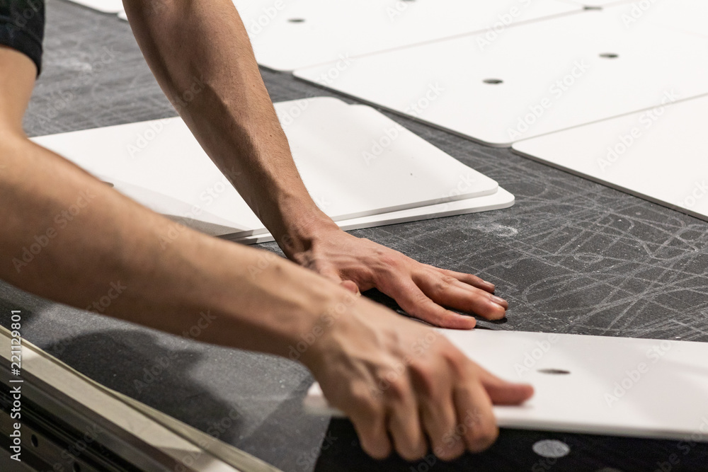 Worker, operating a cnc machine, delivering thin white boards cut into ...