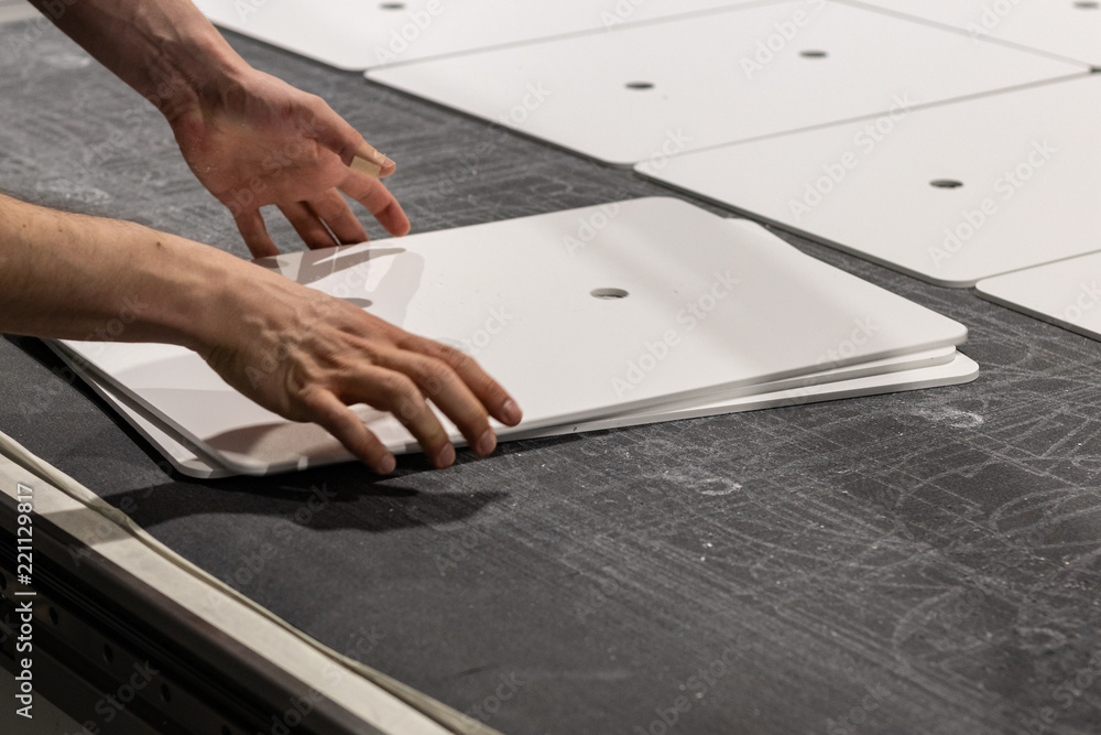 Worker, operating a cnc machine, delivering thin white boards cut into ...