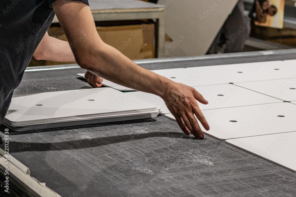 Worker, operating a cnc machine, delivering thin white boards cut into ...