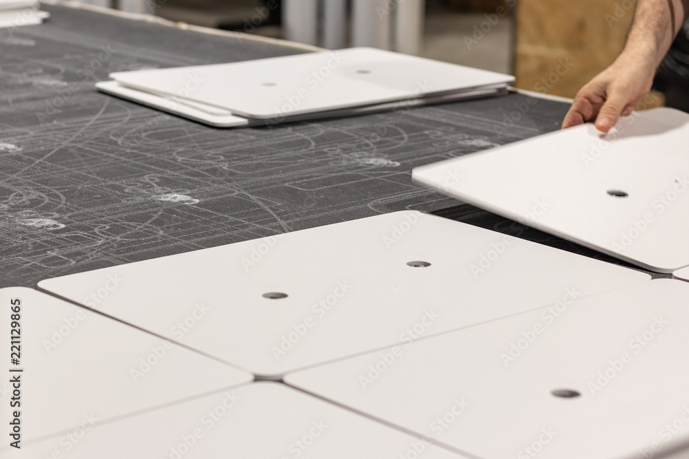 Worker, operating a cnc machine, delivering thin white boards cut into ...