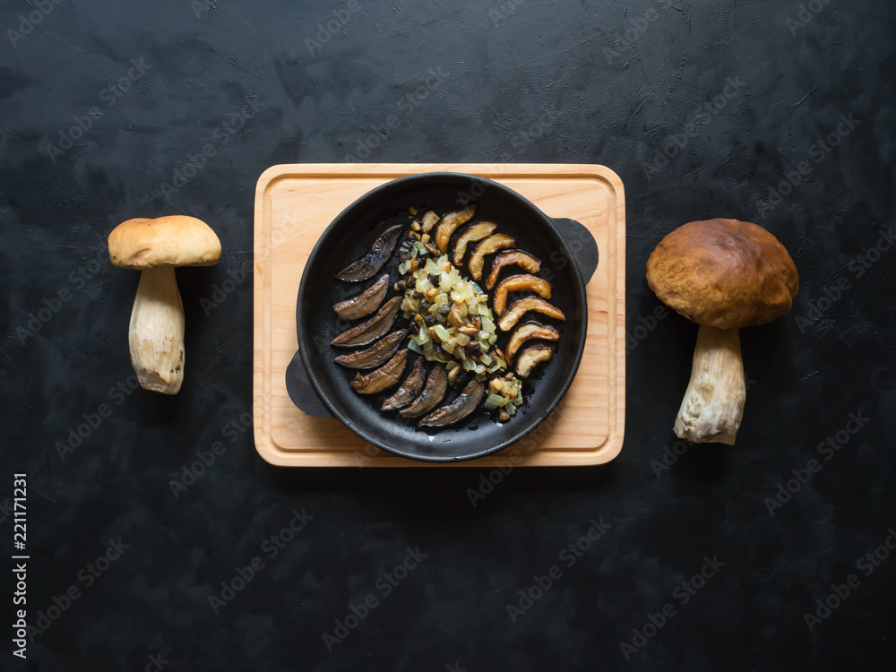 Cooking penny bun. Fried cepes in a iron pan on the black table. Top ...