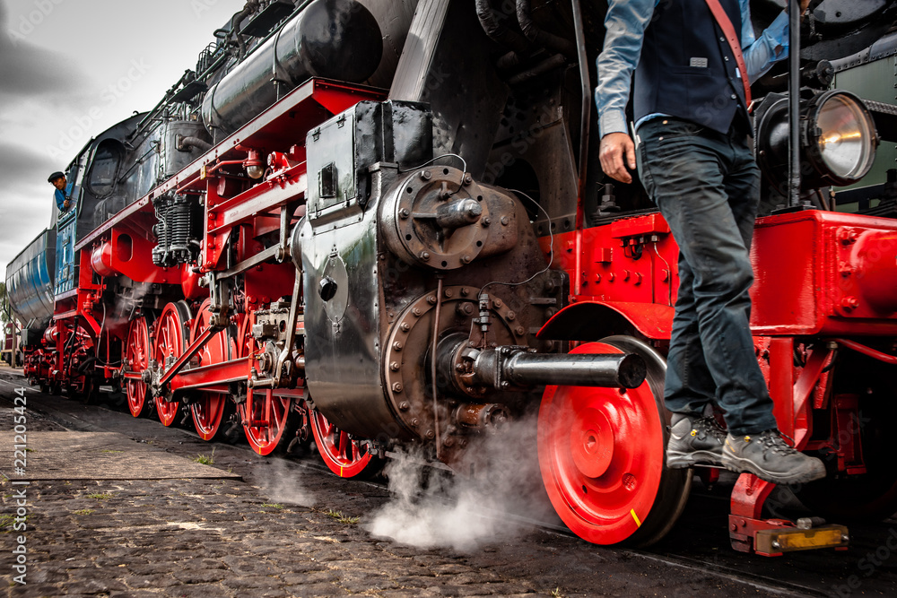 Steamy and rolling old locomotive with red steel wheels on on-site ...