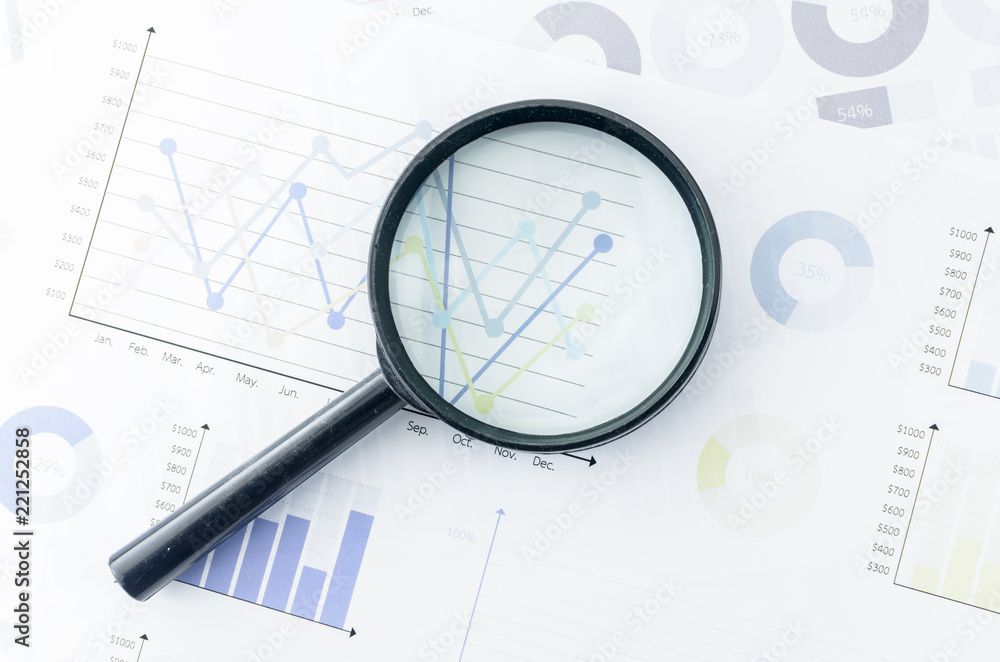 Magnifying with Business Graphs finance document. Stock Photo | Adobe Stock