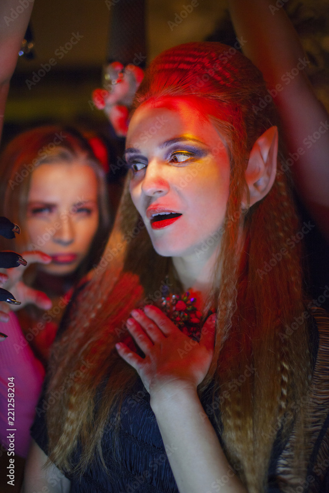 Halloween concept. Portrait of a elf red-haired witch in black dress ...