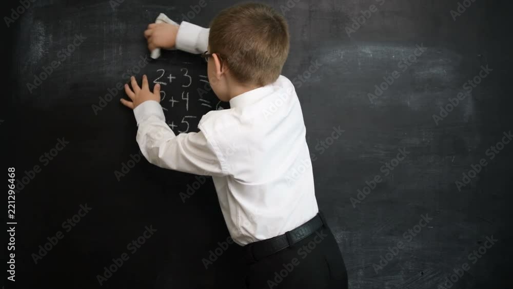 Young boy washing blackboard after solving maths expressions. Creative ...